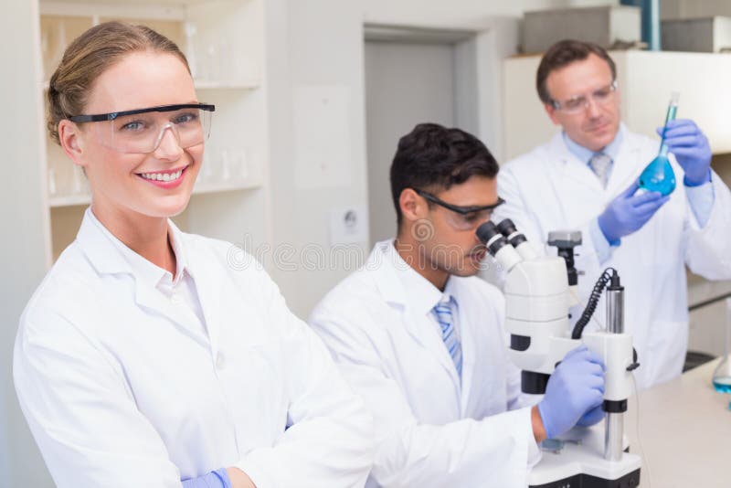 Smiling Scientist Looking at Camera while Colleagues Working with ...
