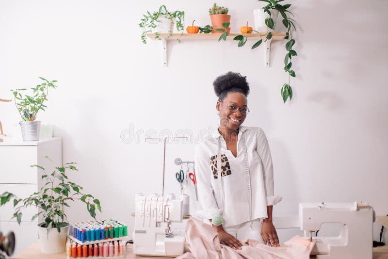 Smiling Seamstress Looking at Camera with Sewing Machine Stock Photo ...