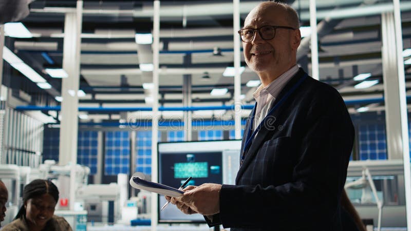 Smiling Senior Engineer in Solar Panels Plant Reading Documentation ...