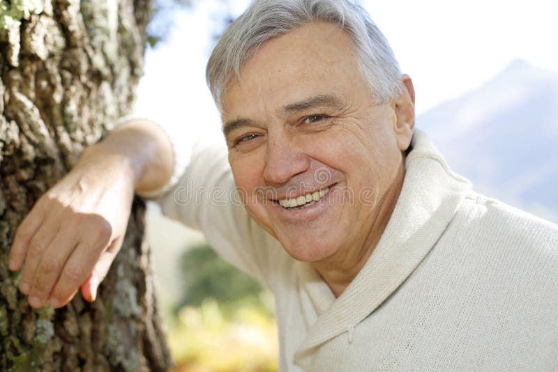 Smiling Senior Man Leaning on Tree Stock Photo - Image of forest, fall ...