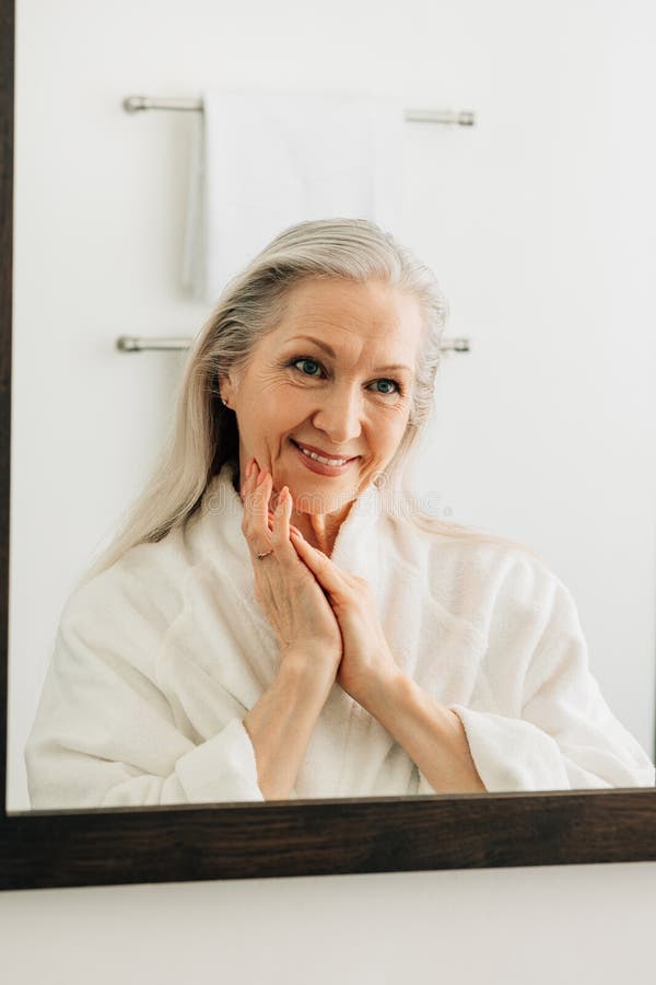Smiling Senior Woman Looking at Her Reflection in Bathroom Mirror Stock ... Smiling Senior Woman Looking at Her Reflection in Bathroom Mirror Stock ...