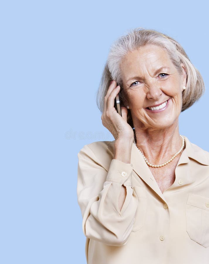 Smiling Senior Woman Using Cell Phone Against Blue Background Stock ...