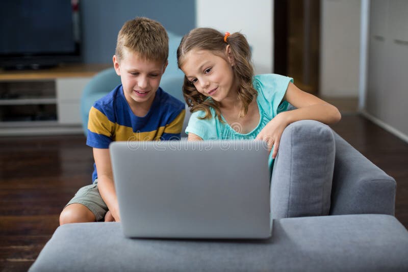 Smiling Siblings Using Laptop in Living Room Stock Photo - Image of ...