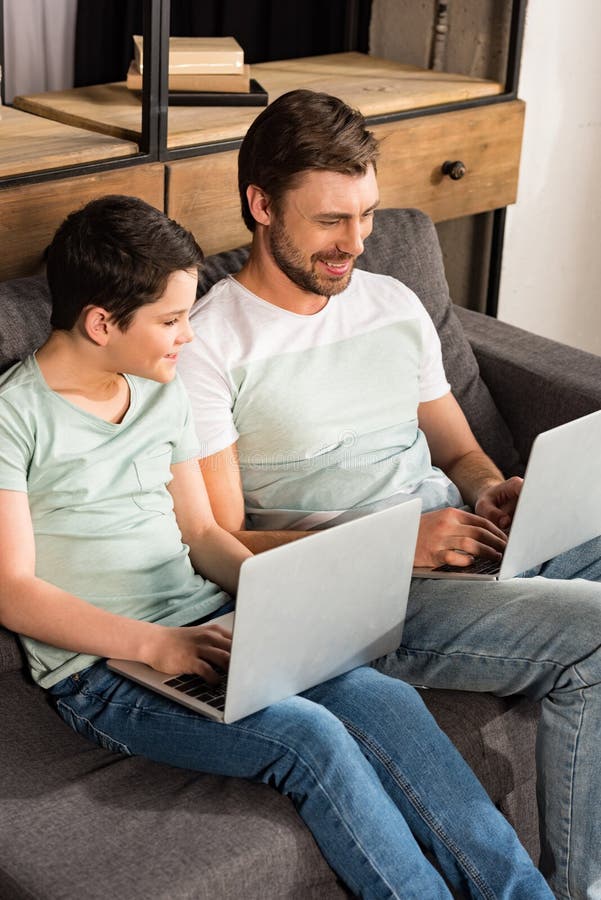 Son and Dad Using Laptops in Living Room Stock Image - Image of indoors ...