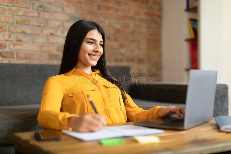 Smiling Spanish Lady Student Using Laptop and Taking Notes, Studying ...
