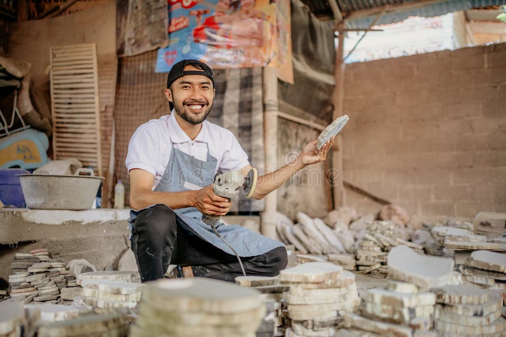 Smiling Stone Craftsman Squats while Holding Stone Slabs and Smoothing ...