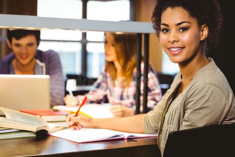 Smiling Student Sitting at Desk Writing on Notepad Stock Photo - Image ...