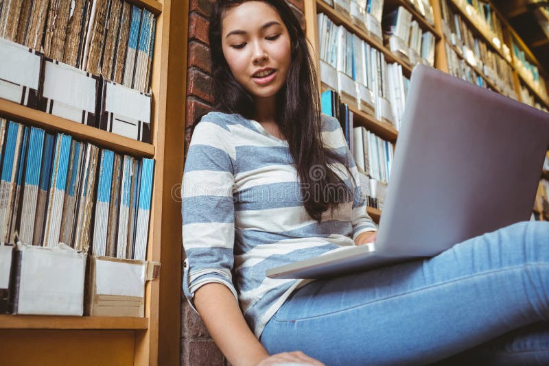 Smiling Student Sitting on the Floor Against Wall in Library Studying ...