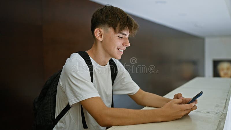 Smiling Teenage Boy with Backpack Using Smartphone at University Campus ...