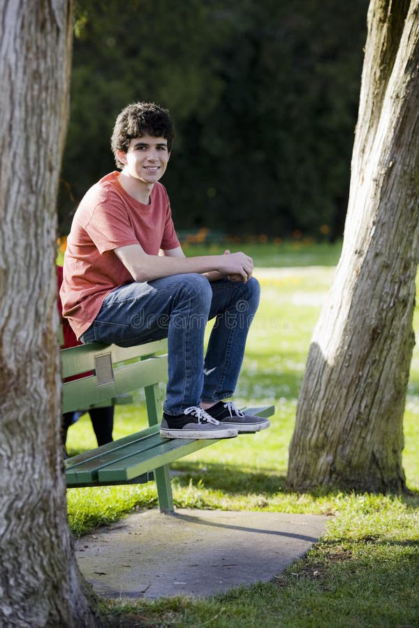 Smiling Teenage Boy Sitting on Bench Stock Photo - Image of park ...