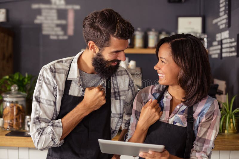Waitress Using Digital Tablet while Waiter Preparing Coffee in ...