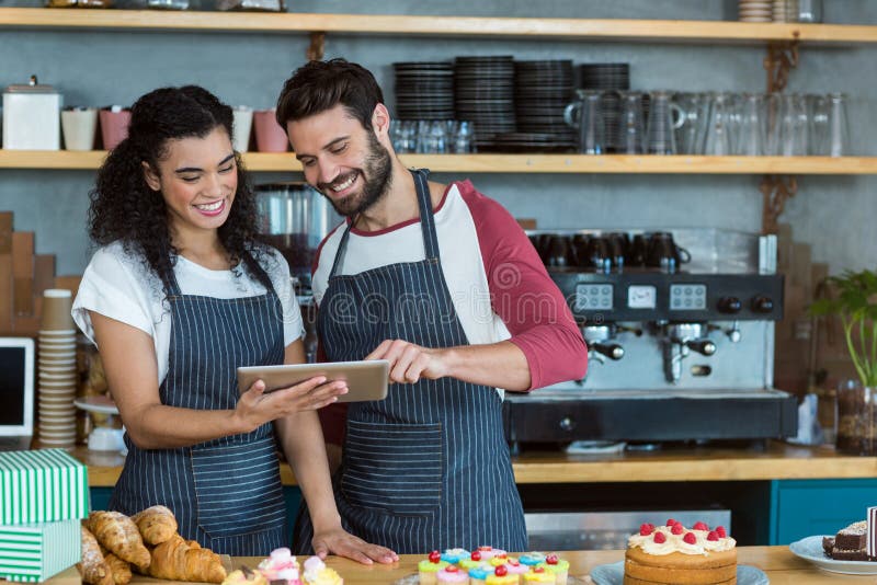 Smiling Waiter and Waitress Using Digital Tablet at Counter Stock Image ...