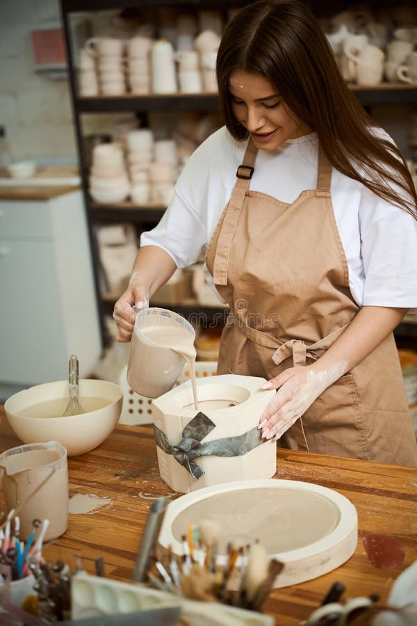 Smiling Woman in Apron Pouring Pottery Mixture into a Mold in Studio ...