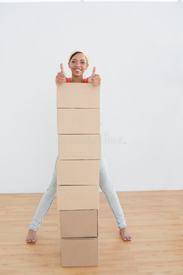 Smiling Woman Gesturing Thumbs Up with Stack of Boxes in New House ...