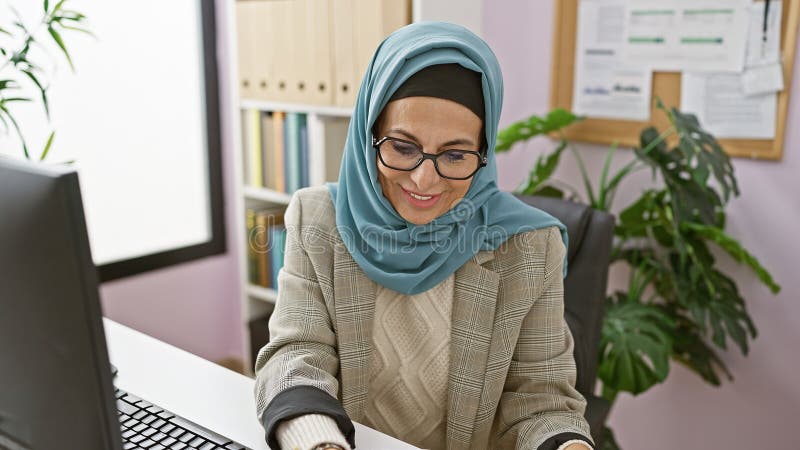 Smiling Woman with Hijab Using Computer in Modern Office, Exemplifying ...