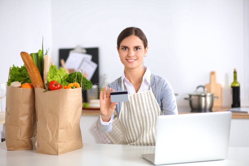 Smiling Woman Online Shopping Using Computer and Credit Card in Kitchen ...