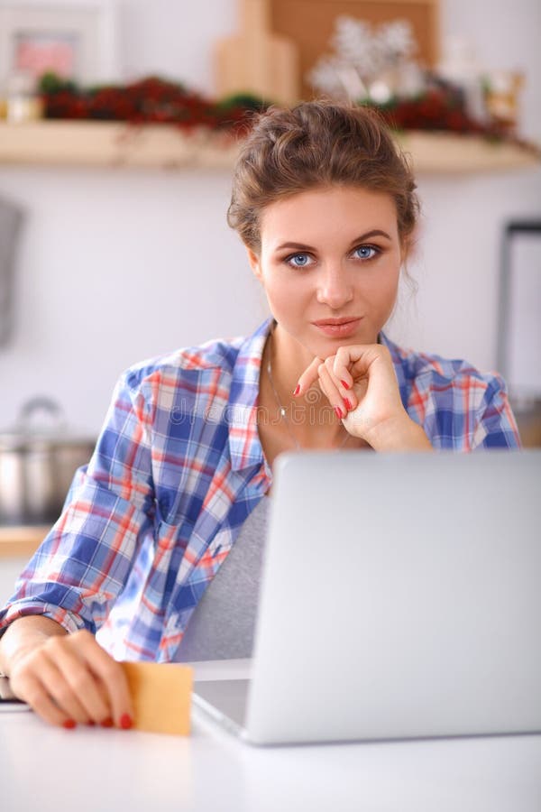 Smiling Woman Online Shopping Using Computer and Credit Card in Kitchen ...