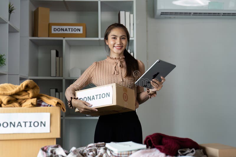 Smiling Woman Organizing Donations with Tablet in Modern Office Setting ...