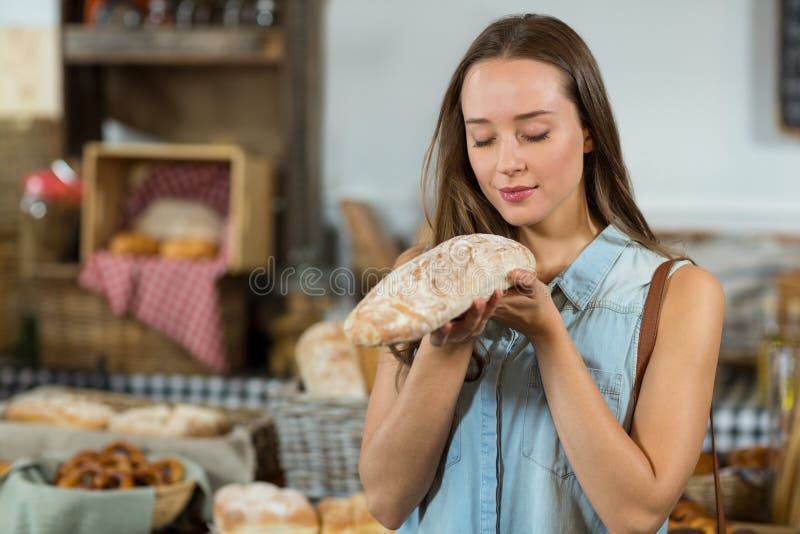 Smiling Woman Smelling a Round Loaf of Bread at Counter Stock Photo ...