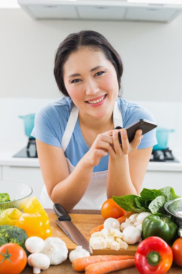 Smiling Woman Text Messaging in Front of Vegetables in Kitchen Stock ...
