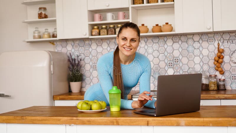 Smiling Woman Using Computer in Modern Kitchen. Healthy Lifestyle ...