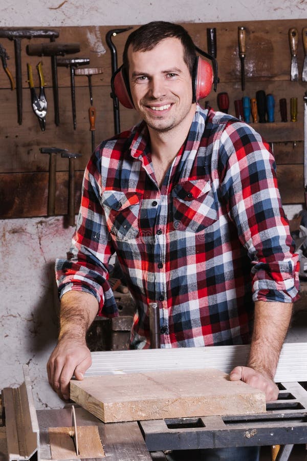 Smiling Woodworker. Cheerful Young Male Carpenter Leaning at the ... Smiling Woodworker. Cheerful Young Male Carpenter Leaning at the ...