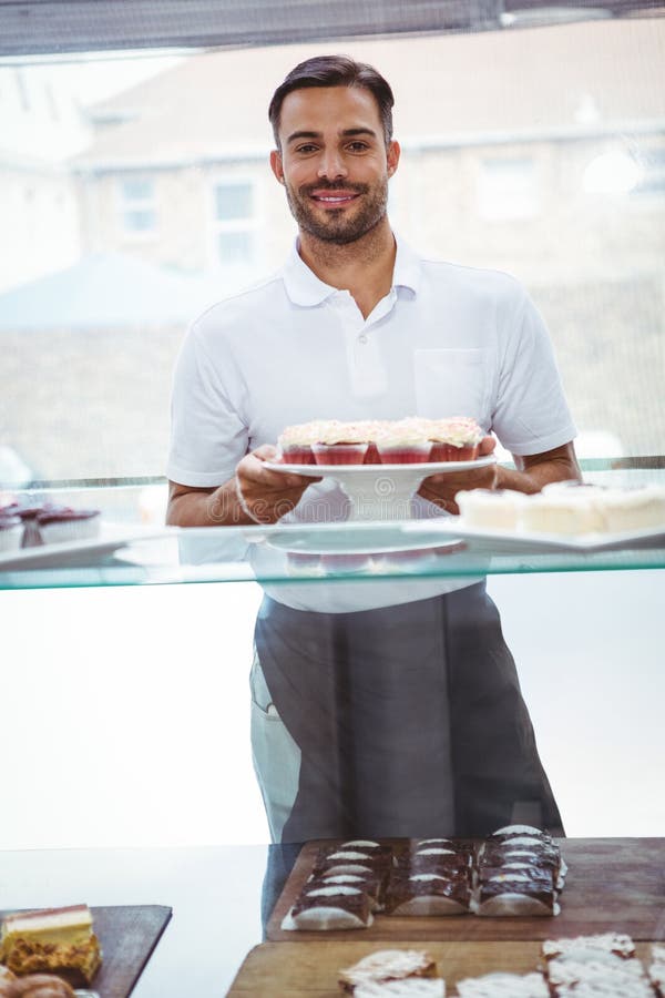Smiling Worker Holding Cupcakes Behind the Counter Stock Image - Image ...