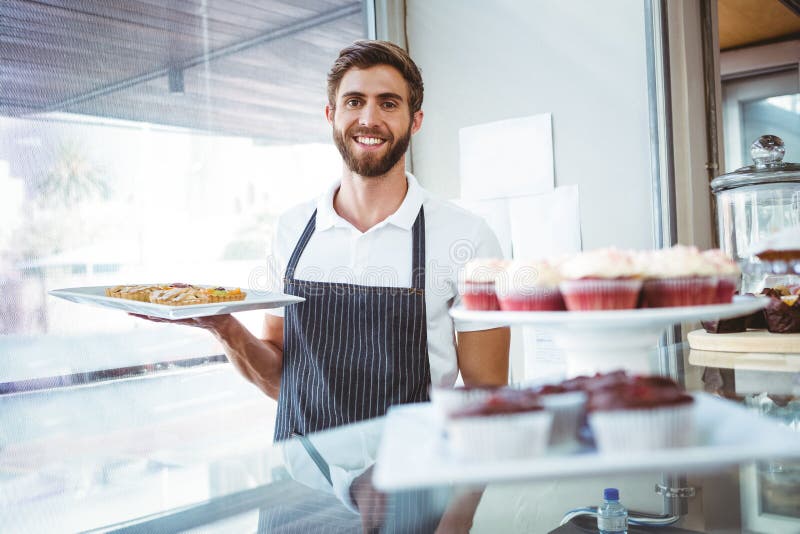 Smiling Worker Holding Pastry Behind the Counter Stock Photo - Image of ...