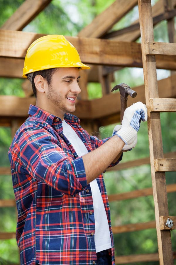 Smiling Worker Using Hammer in Wooden Cabin Stock Image - Image of ...