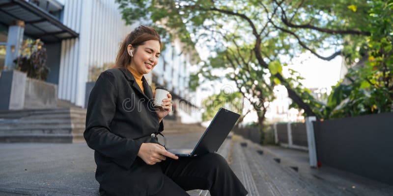 Smiling Young Asian Business Woman Using Laptop Sitting Outdoor. Hybrid ... Smiling Young Asian Business Woman Using Laptop Sitting Outdoor. Hybrid ...