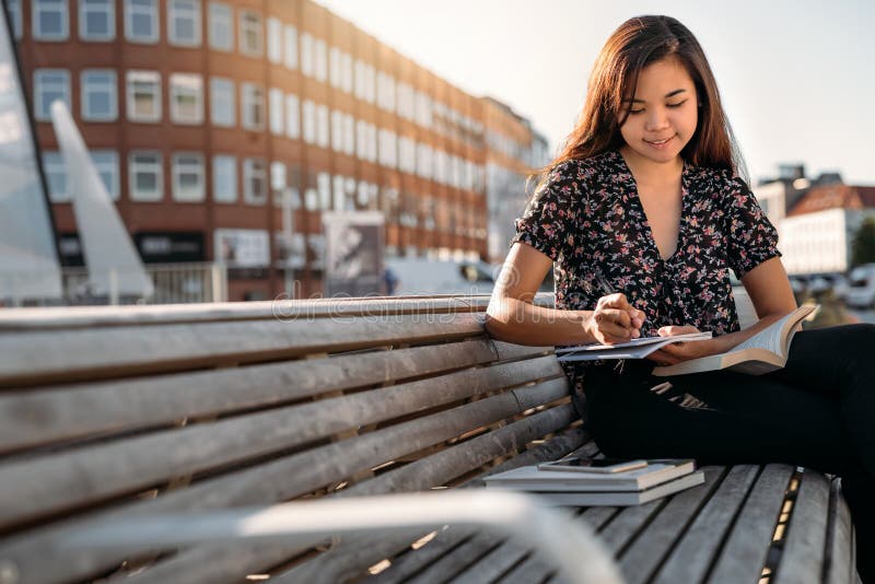 Smiling Asian College Student Sitting on Campus Studying between ...