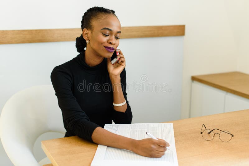 Smiling Young Black Business Woman on Phone Taking Notes in Office ...