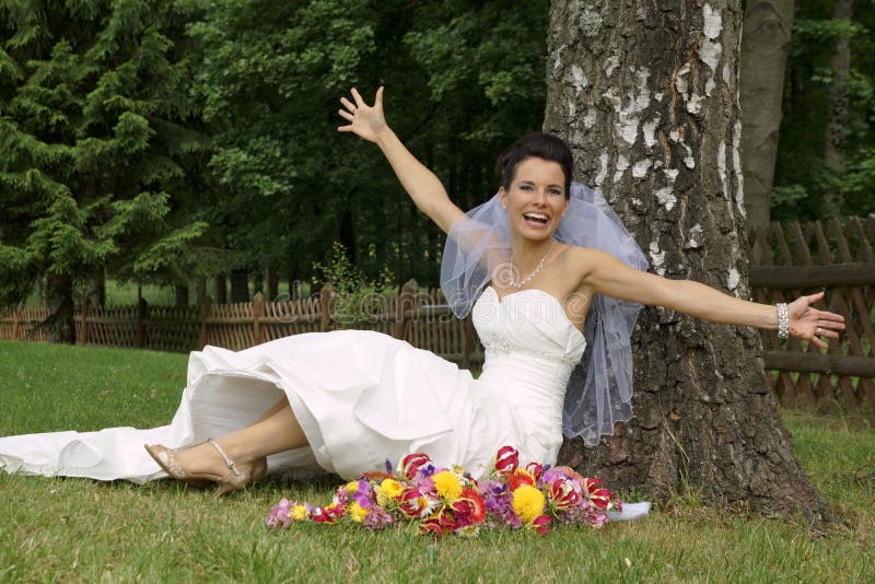 Smiling Young Bride Sitting Under Tree Stock Photo - Image of bride ...