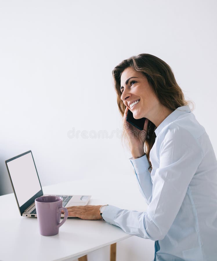 Smiling Young Brunette with Laptop on Table and Cup Talking on Phone ...