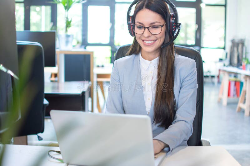 Smiling Young Business Woman with Headset Using Laptop in Office. Stock ...