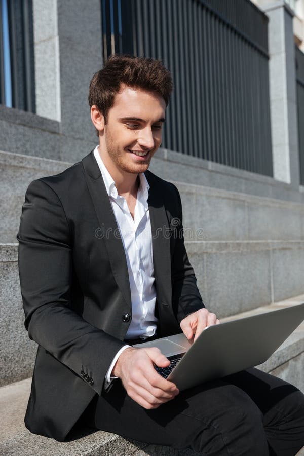 Smiling Young Businessman Sitting Outdoors Using Laptop Stock Image ...