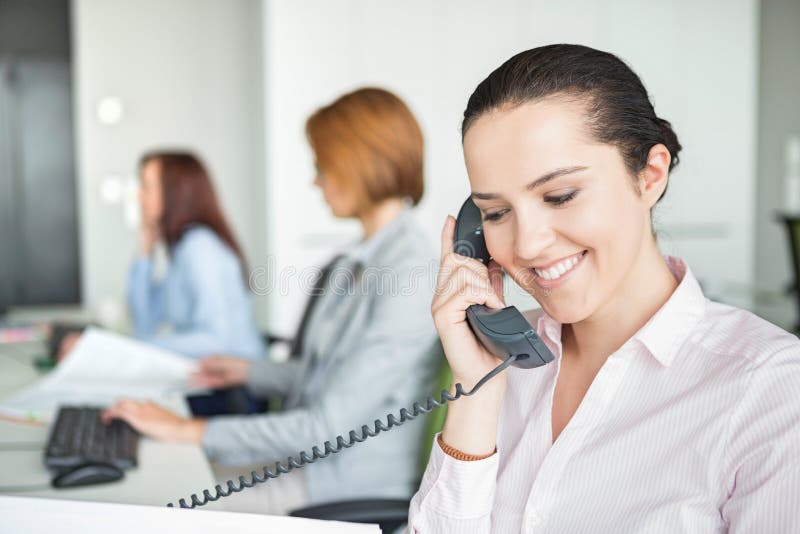 Smiling Young Businesswoman Using Landline Phone in Office Stock Image ... Smiling Young Businesswoman Using Landline Phone in Office Stock Image ...