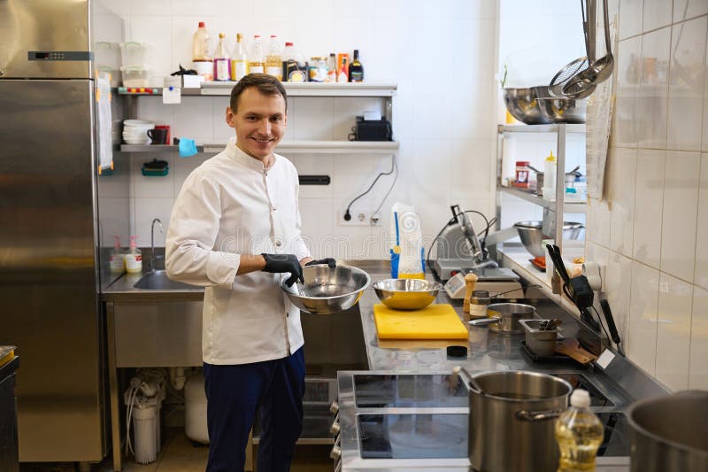 Smiling Young Chef Preparing Food in a Restaurant Kitchen Stock Photo ...