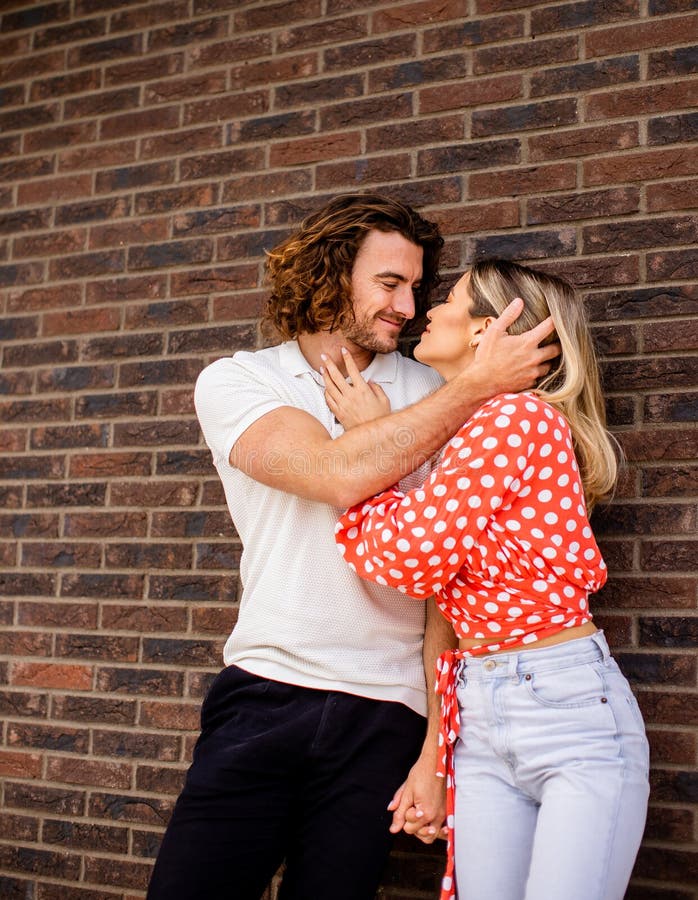 Smiling Young Couple in Love in Front of House Brick Wall Stock Photo ...