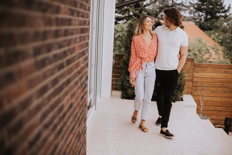 Smiling Young Couple in Love Walking in Front of House Brick Wall Stock ...