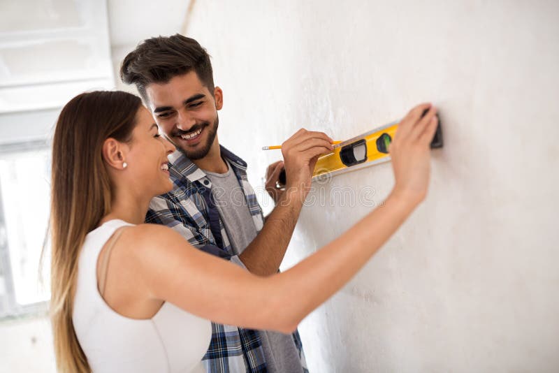 Smiling Young Couple Measuring Wall with Level Tool, Renovation Stock ...