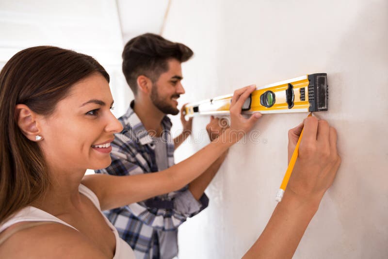 Smiling Young Couple Measuring Wall with Level Tool, Renovation Stock ...
