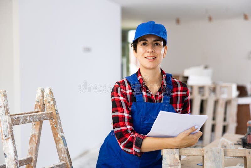 Smiling Young Female Builder Taking Notes at Construction Site Indoors ...