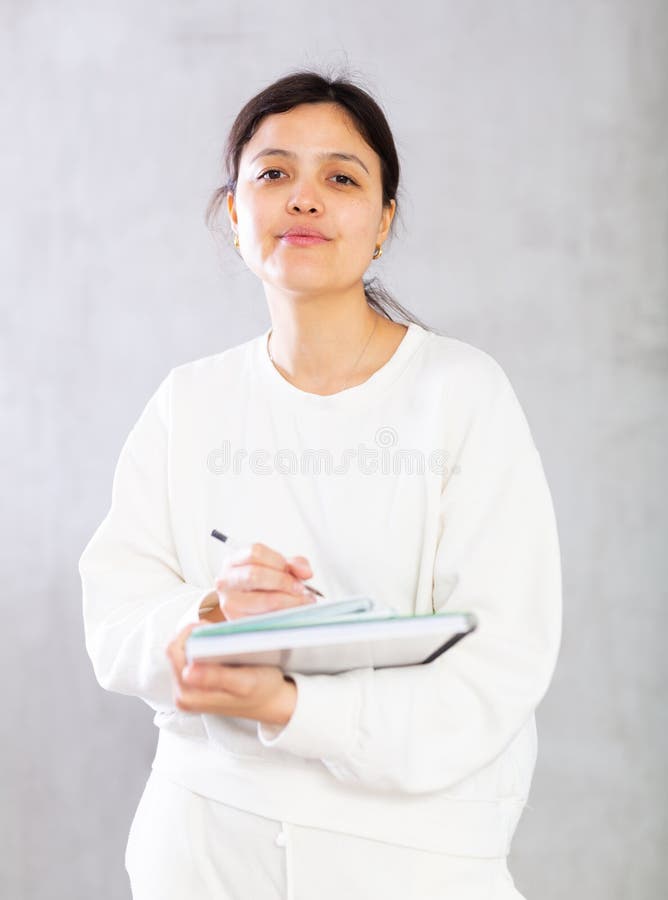 Smiling Young Female Tutor or College Student Writing in Workbooks ... Smiling Young Female Tutor or College Student Writing in Workbooks ...