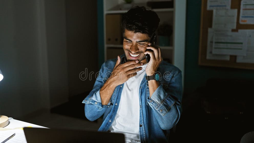 Smiling Young Hispanic Man Making a Phone Call at Night in a Modern ...