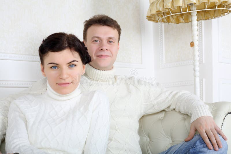 Smiling Young Husband and Wife in White Sweaters Sit on Sofa Stock ...