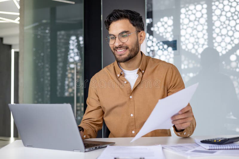 A Smiling Young Indian Man is Working in the Office with a Laptop and ...