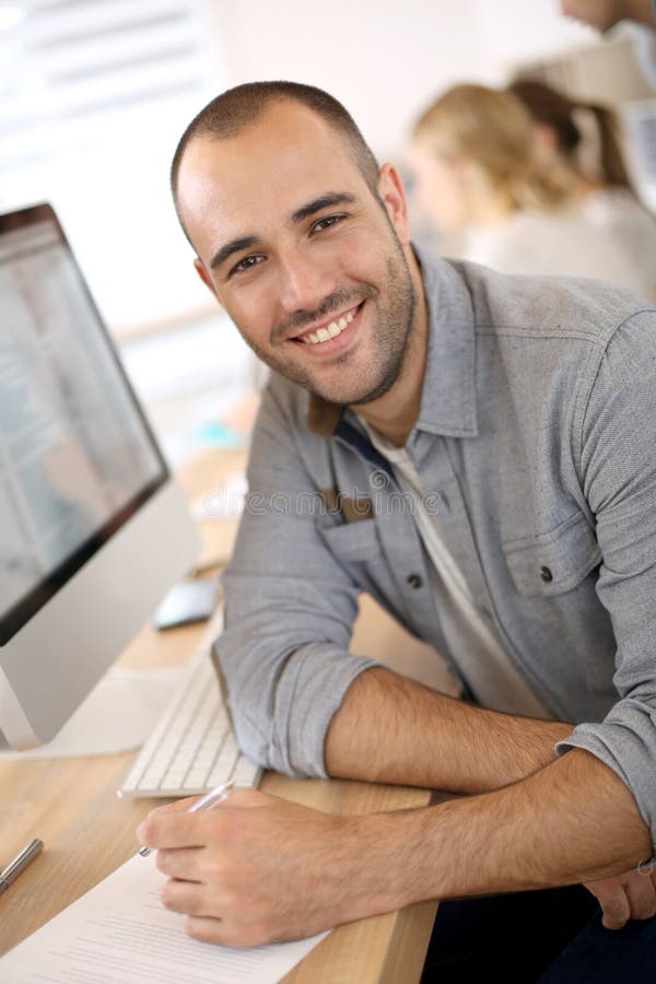 Smiling Young Man at Desk Office Stock Photo - Image of student ...