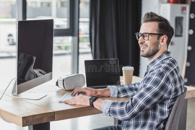 Smiling Young Man in Eyeglasses Using Desktop Computer and Laptop Stock ...