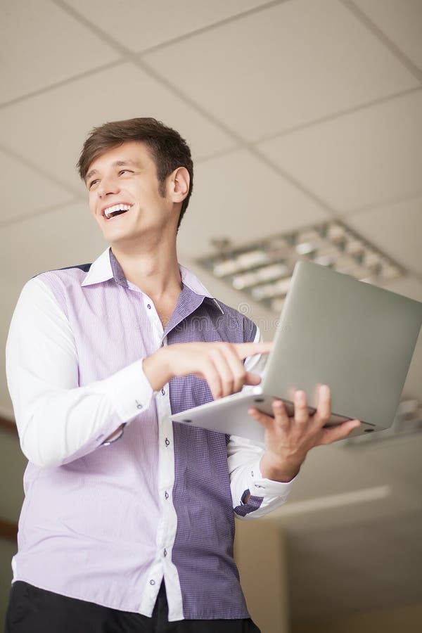 Smiling Young Man Holding Laptop and Typing while Standing Again Stock ...